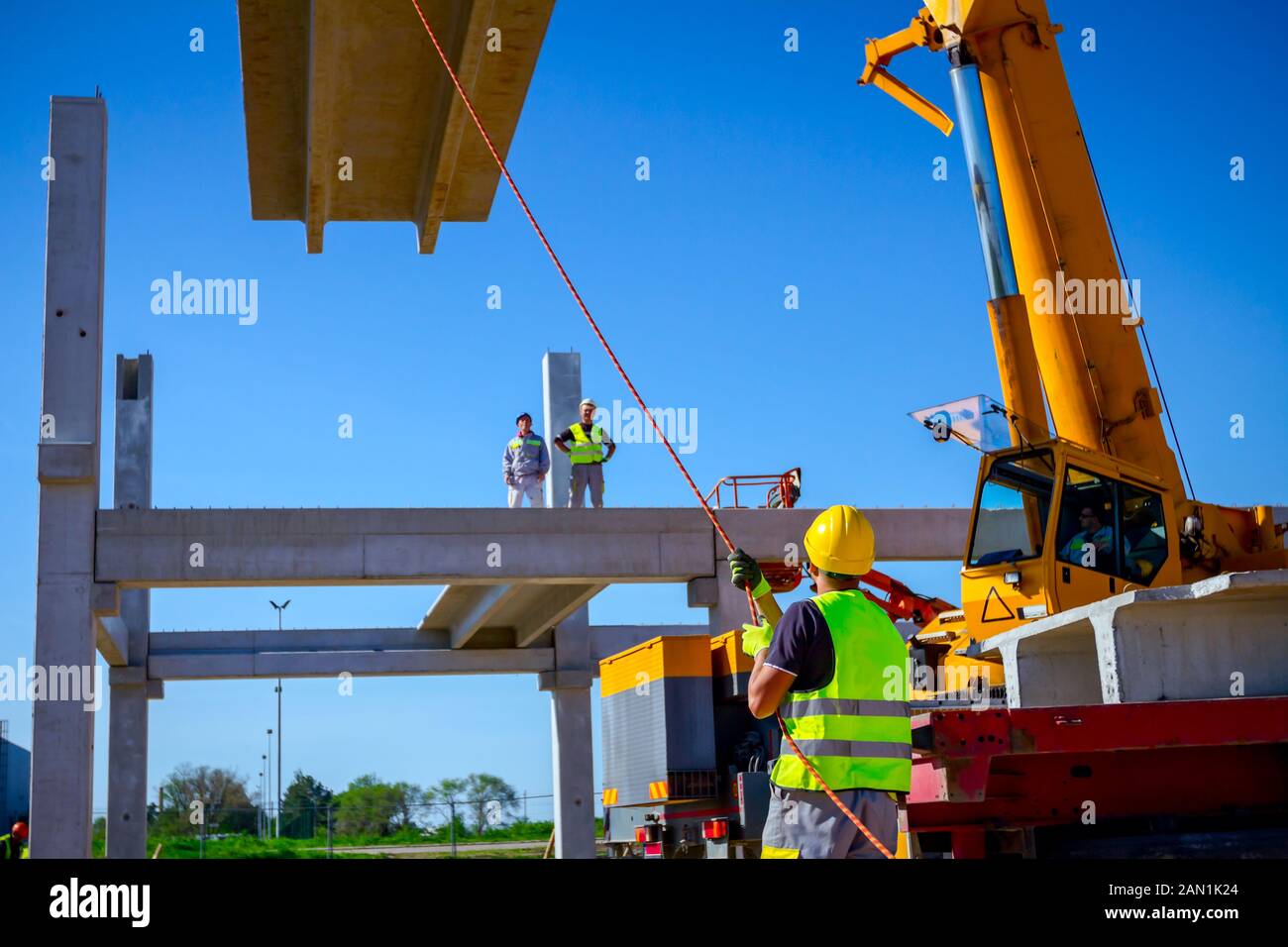 Worker is helping mobile crane with rope to manage concrete joist for ...