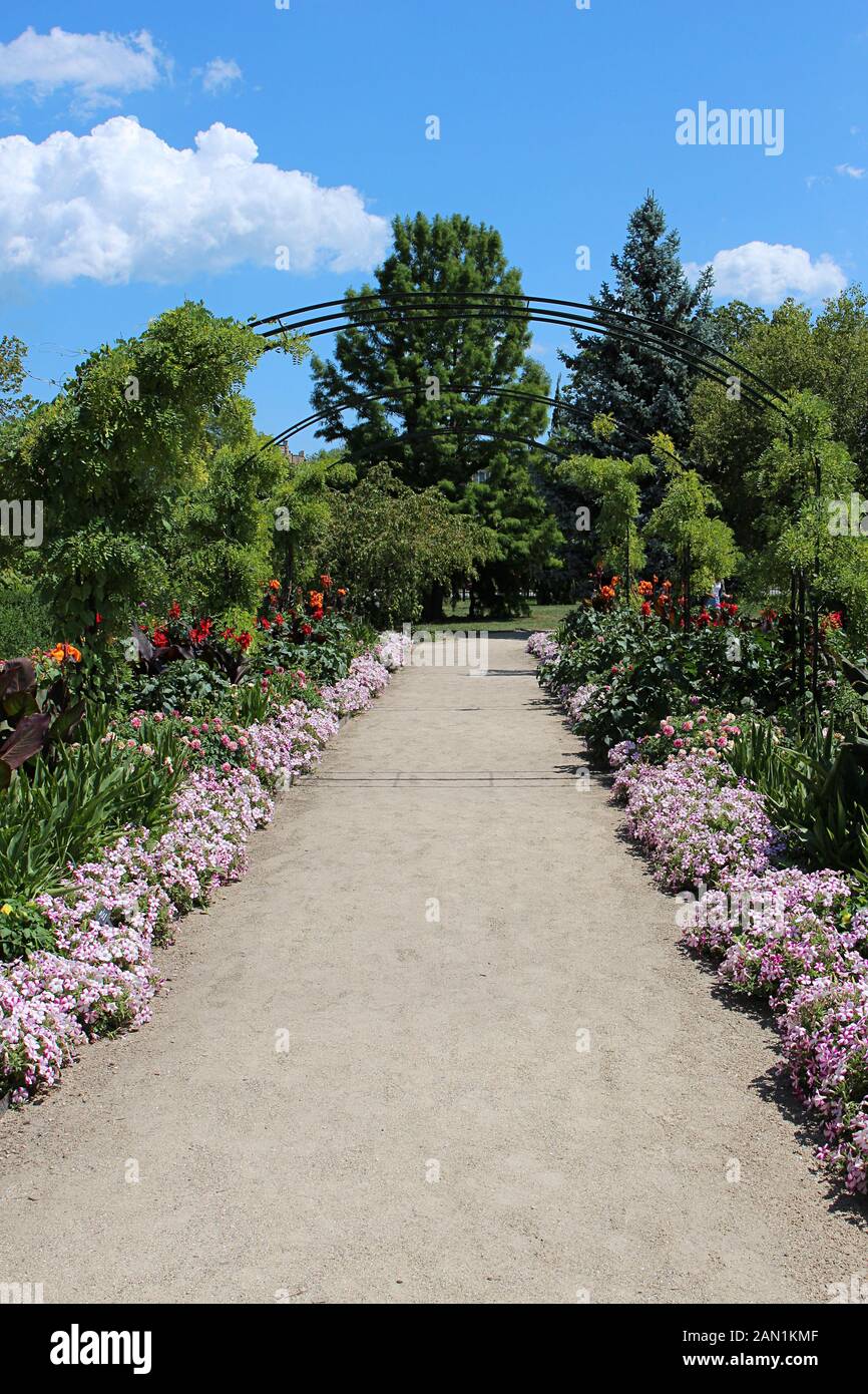 A walking path through a garden leading to a grassy, tree area on a ...