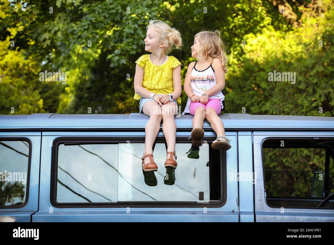 two girls sitting on top of roof of vintage car in summertime Stock ...