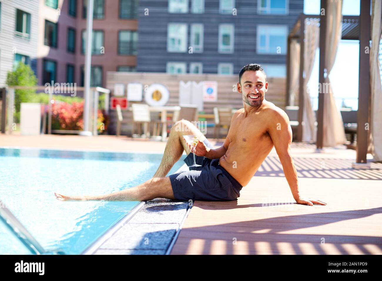 A man relaxes with a drink by the pool Stock Photo - Alamy
