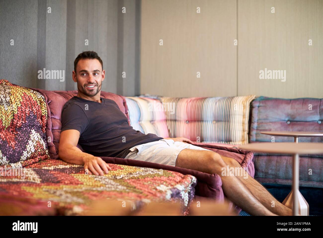 A man relaxes on a comfortable modern couch Stock Photo - Alamy