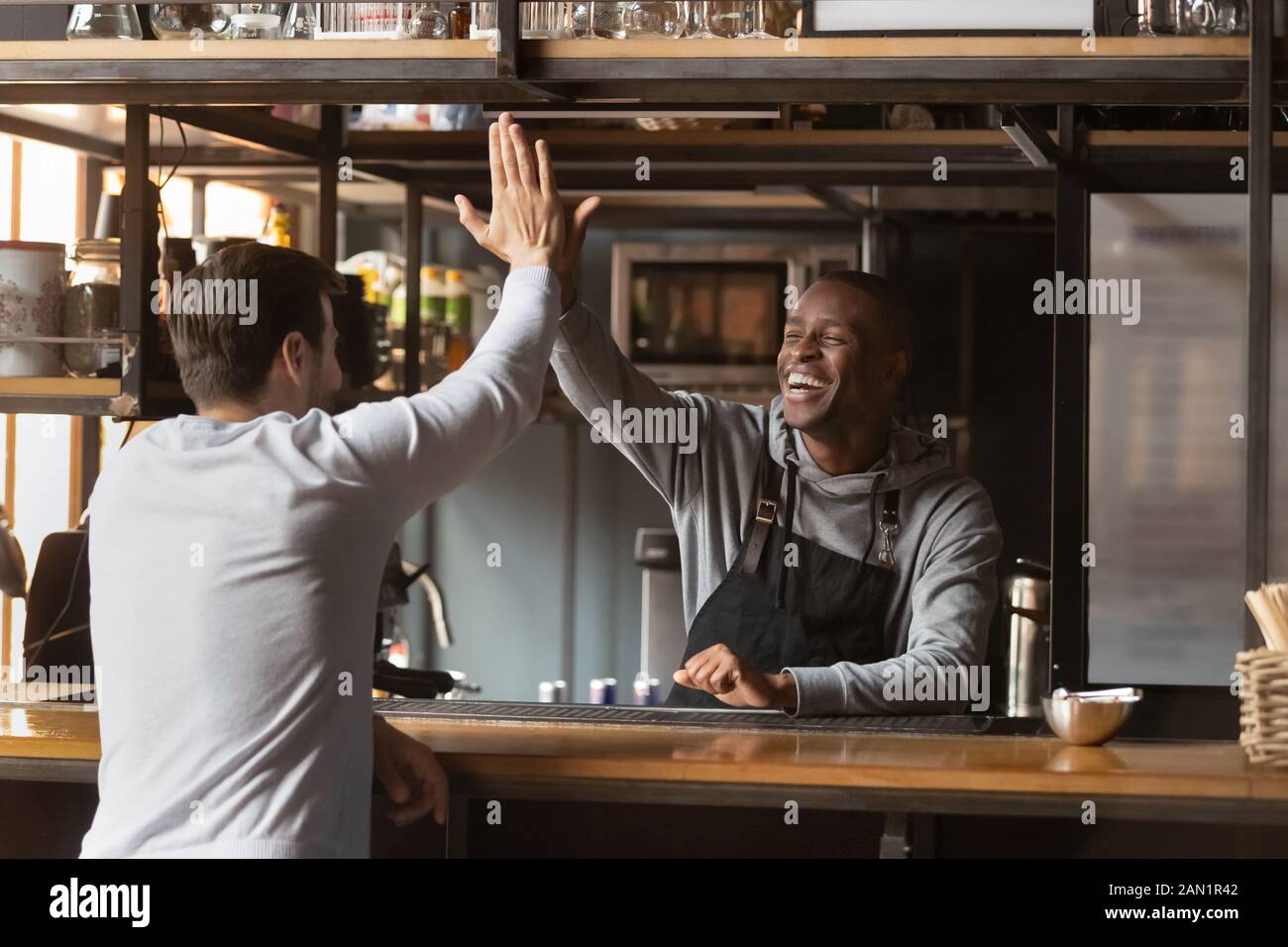 Overjoyed black waiter give high five to male client Stock Photo - Alamy