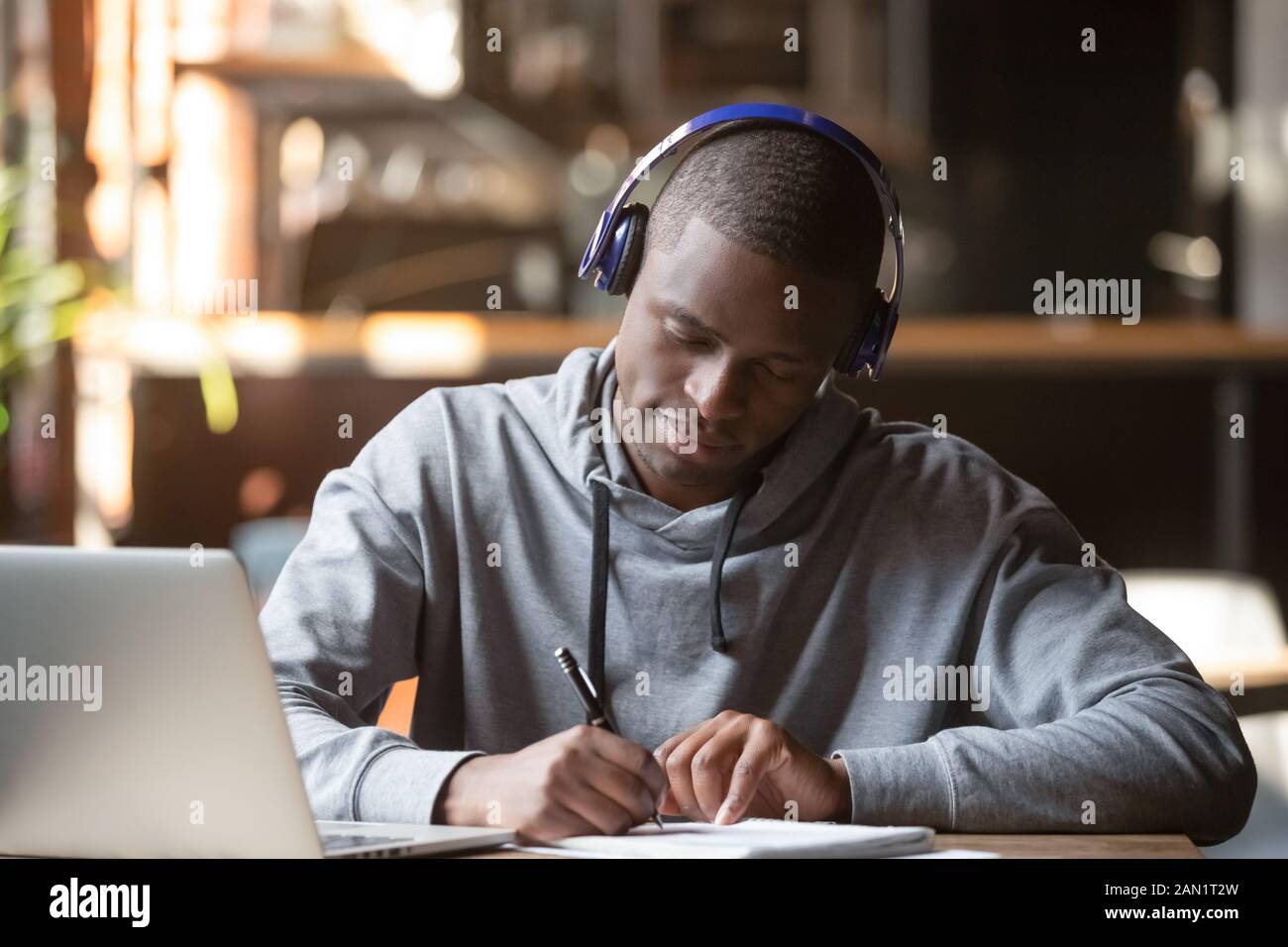 Concentrated black male student in Bluetooth headphones studying Stock ...