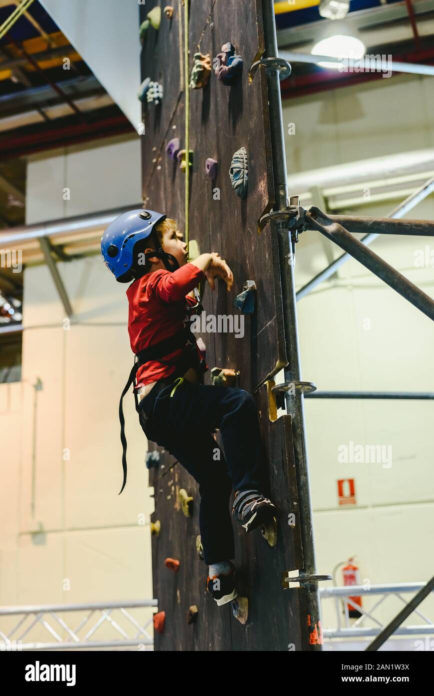 Child on the walls of a climbing wall with the help of a safety rope ...