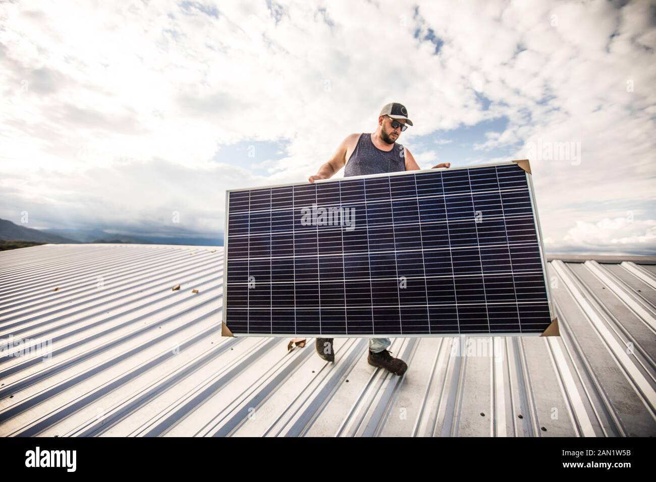 Man carrying solar panel on roof during installation Stock Photo - Alamy