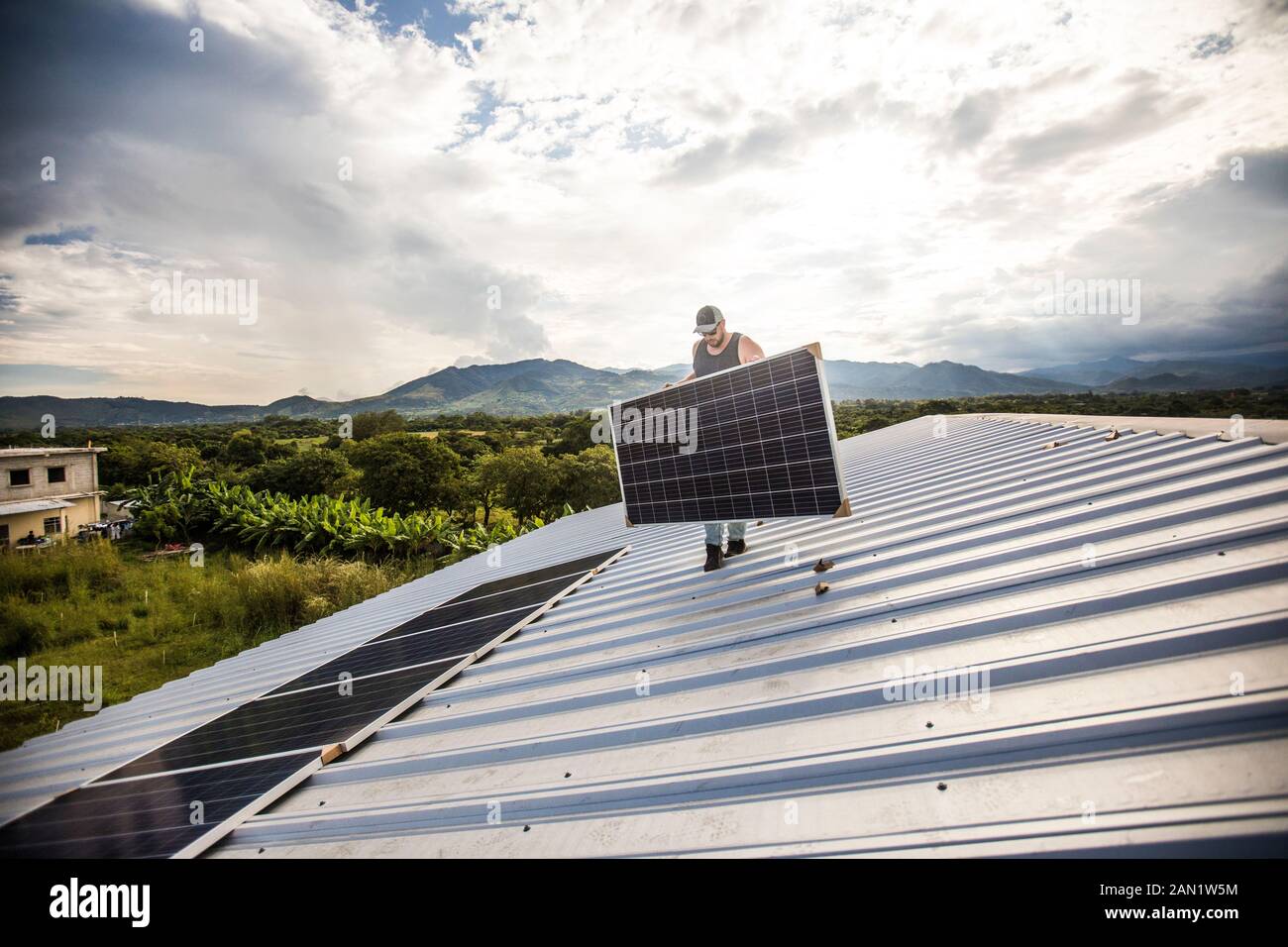 Man carrying solar panel on roof during installation Stock Photo - Alamy