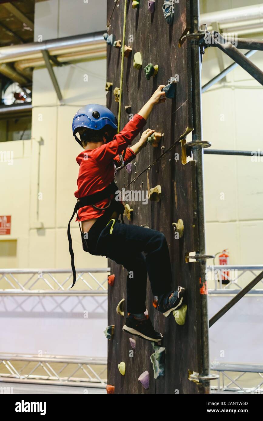 Child on the walls of a climbing wall with the help of a safety rope ...