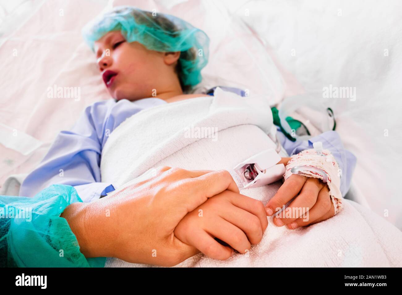 Mother holds her son's hand to encourage her in a hospital bed before ...
