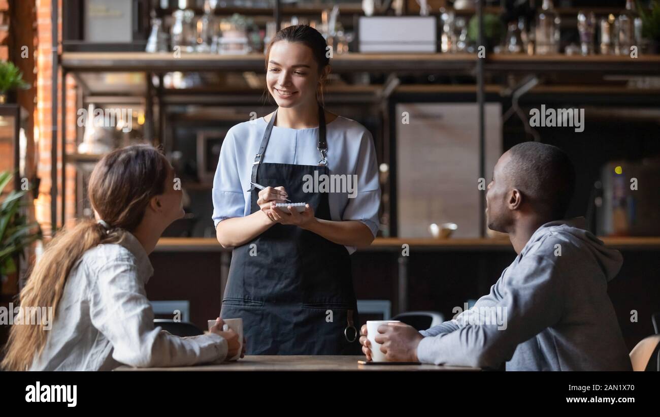 Smiling waitress taking order from multiracial clients Stock Photo - Alamy