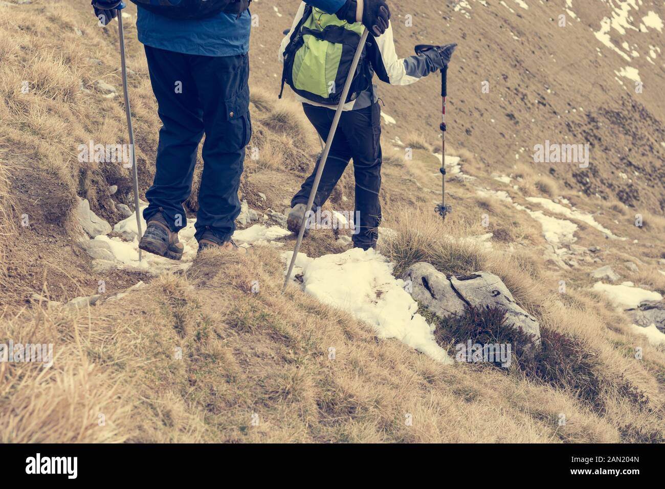 Pair of hikers descending winter traile of grass covered slope Stock ...
