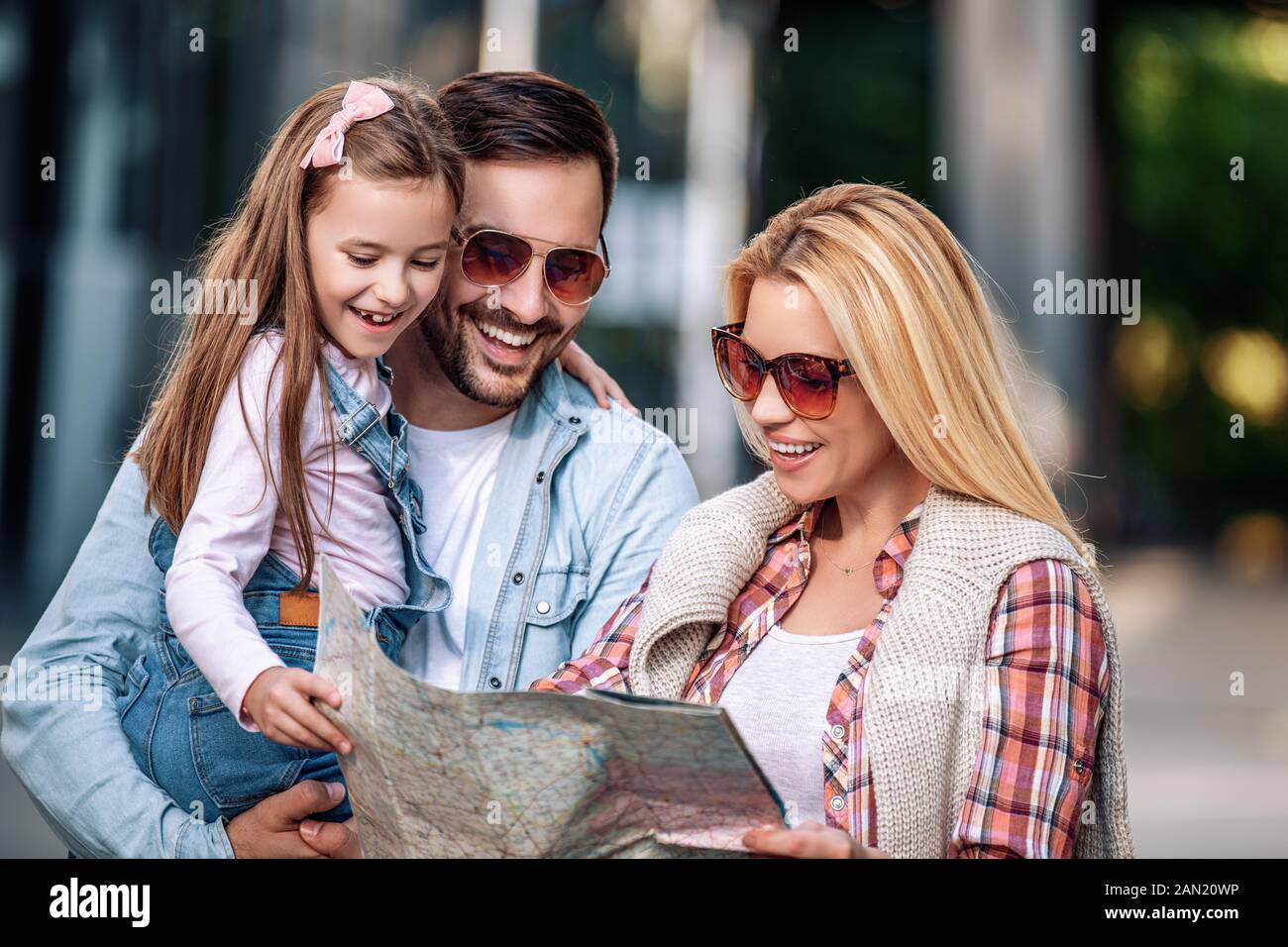 Family of tourists looking for some destination with city map.They are ...