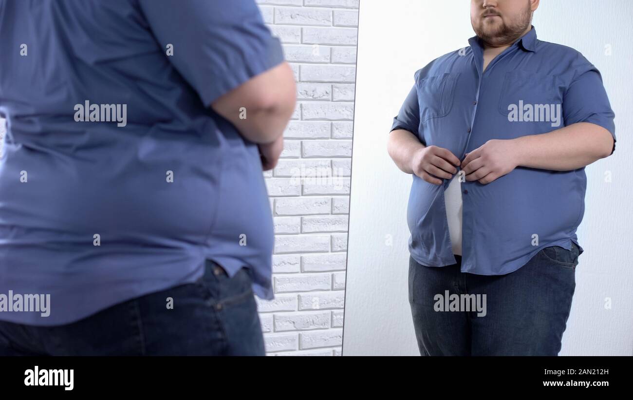 Corpulent man buttoning up tight shirt, oversize clothing problem ...
