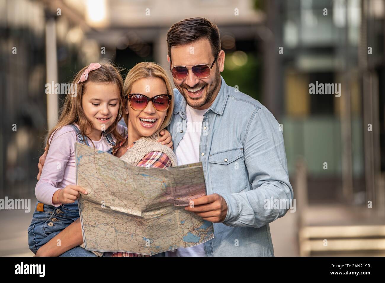 Family of tourists looking for some destination with city map.They are ...