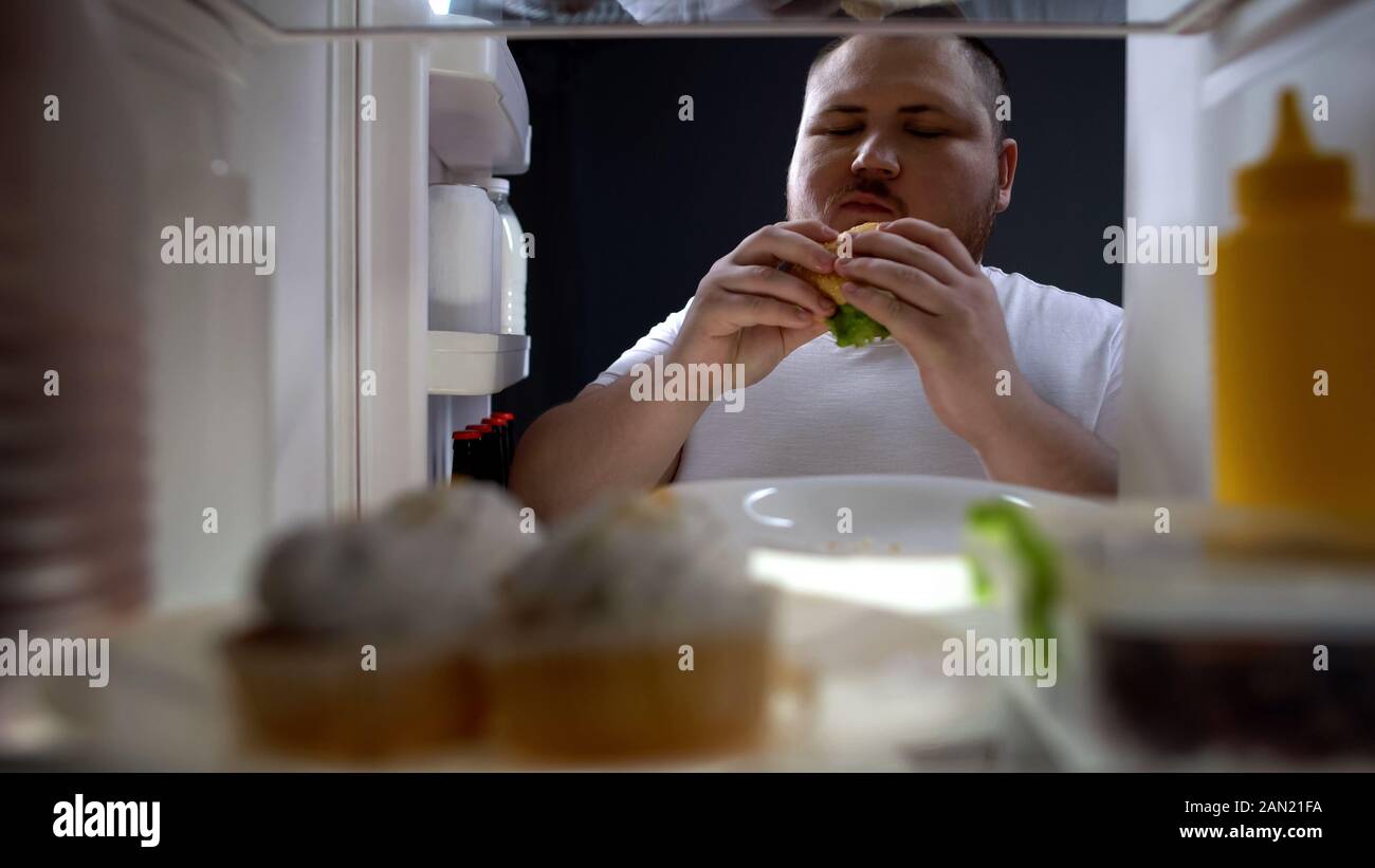 Obese man eating cheeseburger with pleasure, diet failure, unhealthy ...