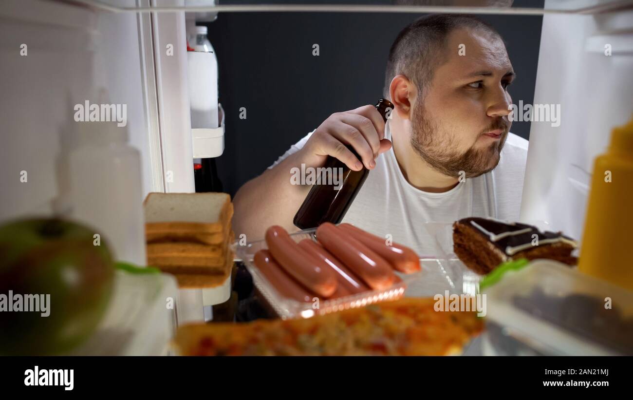 Fat male secretly taking beer bottle from fridge at night, unhealthy ...