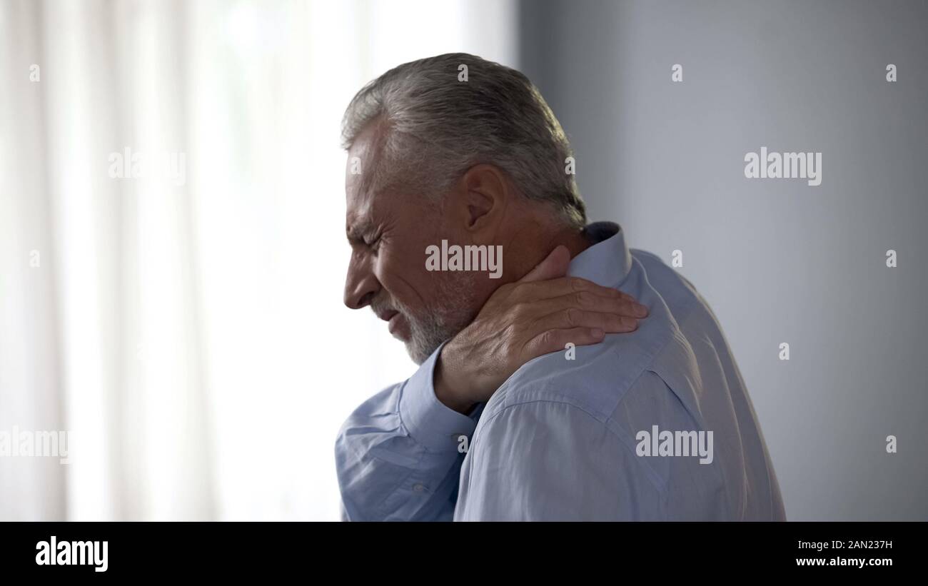 Senior male touching neck in acute pain standing sideways, pain in ...