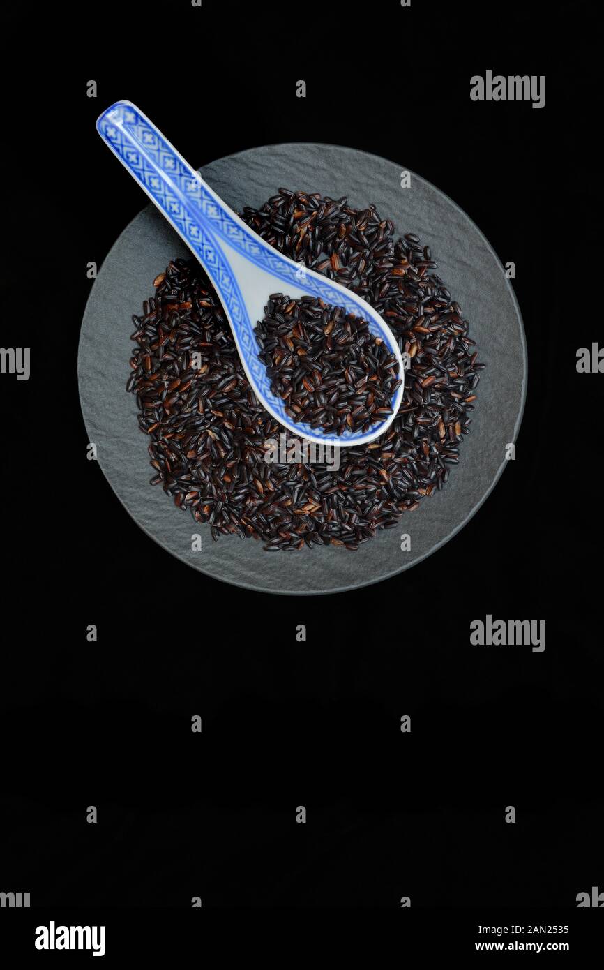 Black rice with spoon on black plate, Germany Stock Photo - Alamy