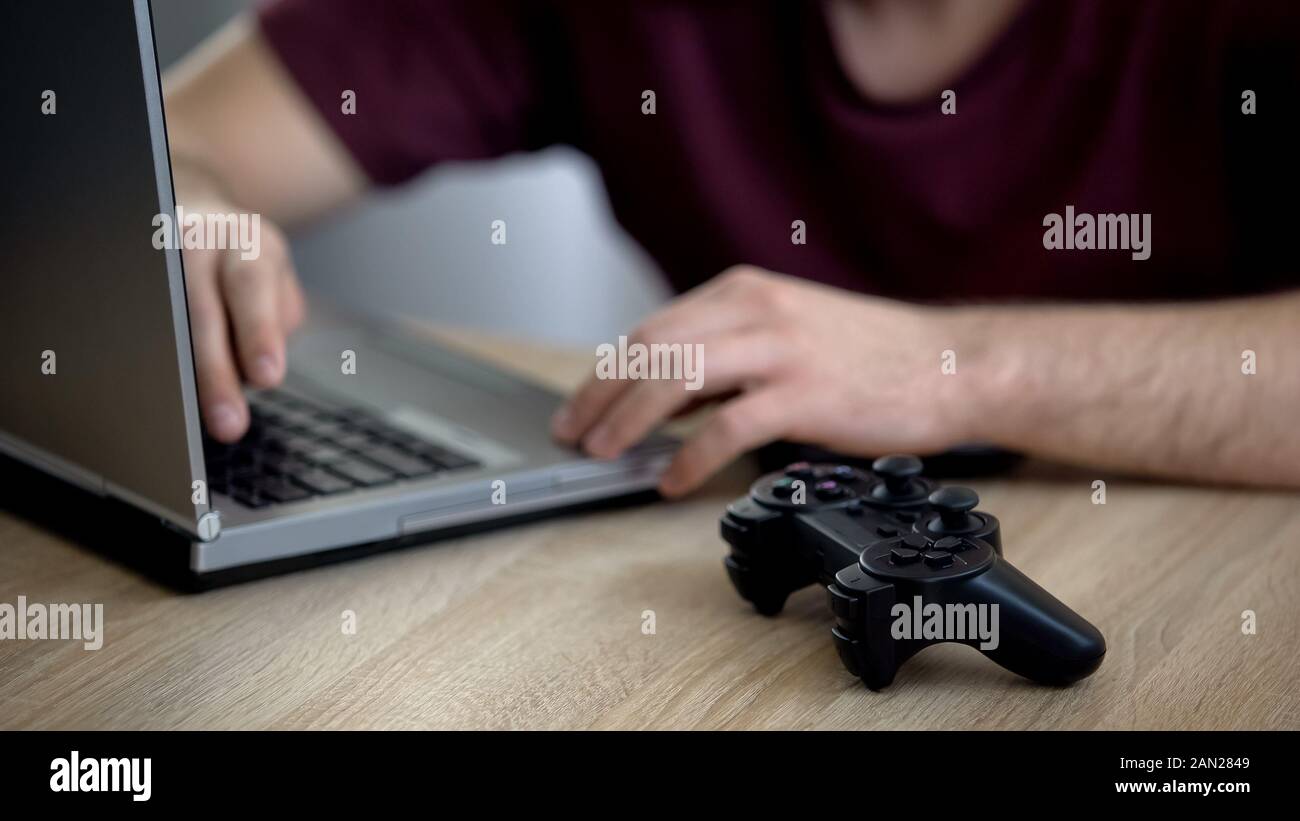Male playing video games, joystick lying on table near laptop, gaming ...