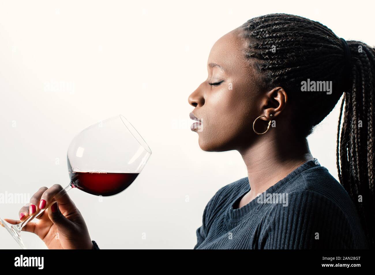 Close up side view portrait of African female wine enthusiast smelling ...
