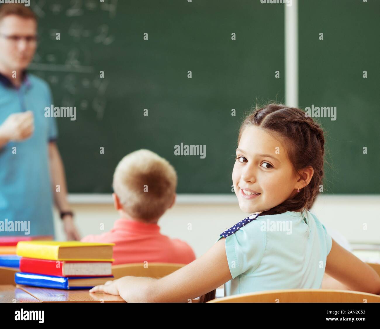 Young male teacher explaining math at the blackboard during a lesson at ...
