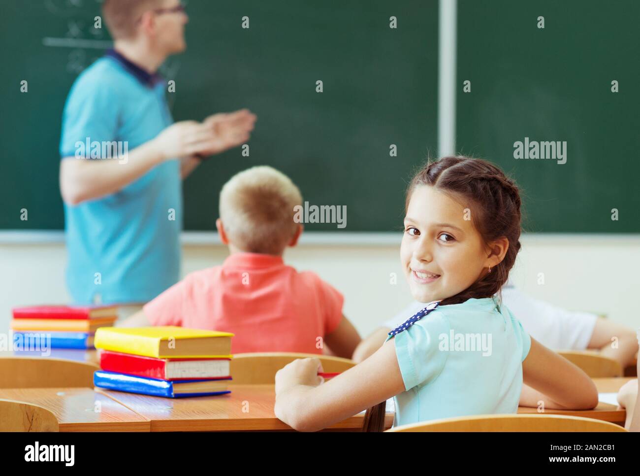 Young male teacher explaining math at the blackboard during a lesson at ...