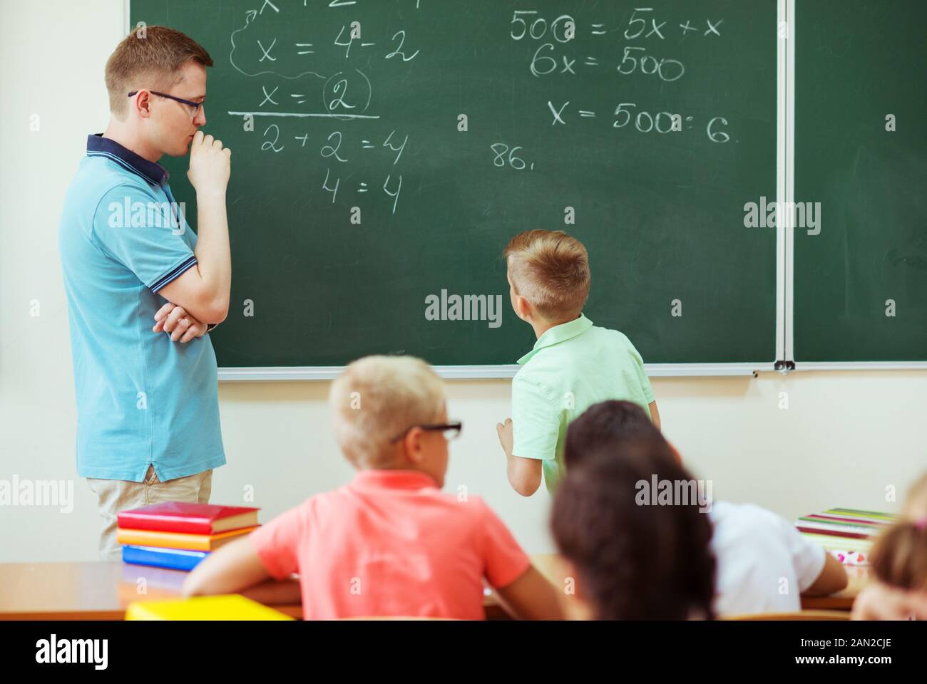 Young male teacher explaining math at the blackboard during a lesson at ...
