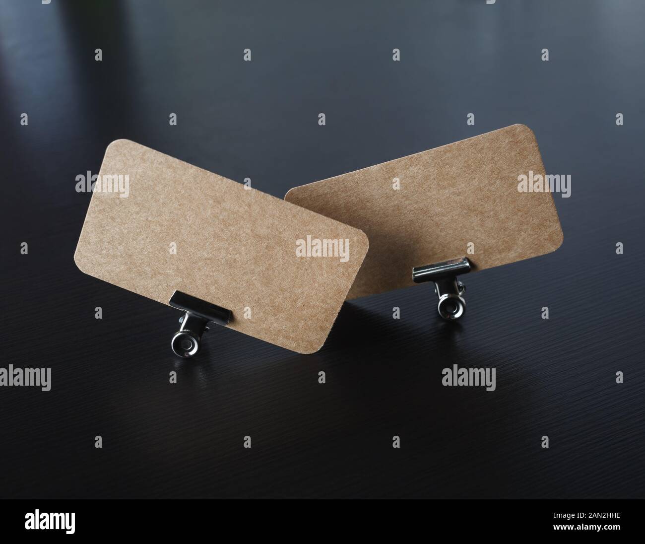 Two blank kraft business cards and metal binder clips on black wooden ...