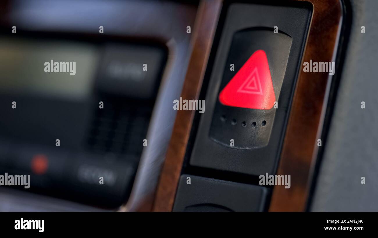 Pressed and glowing emergency car hazard warning flasher button on ...