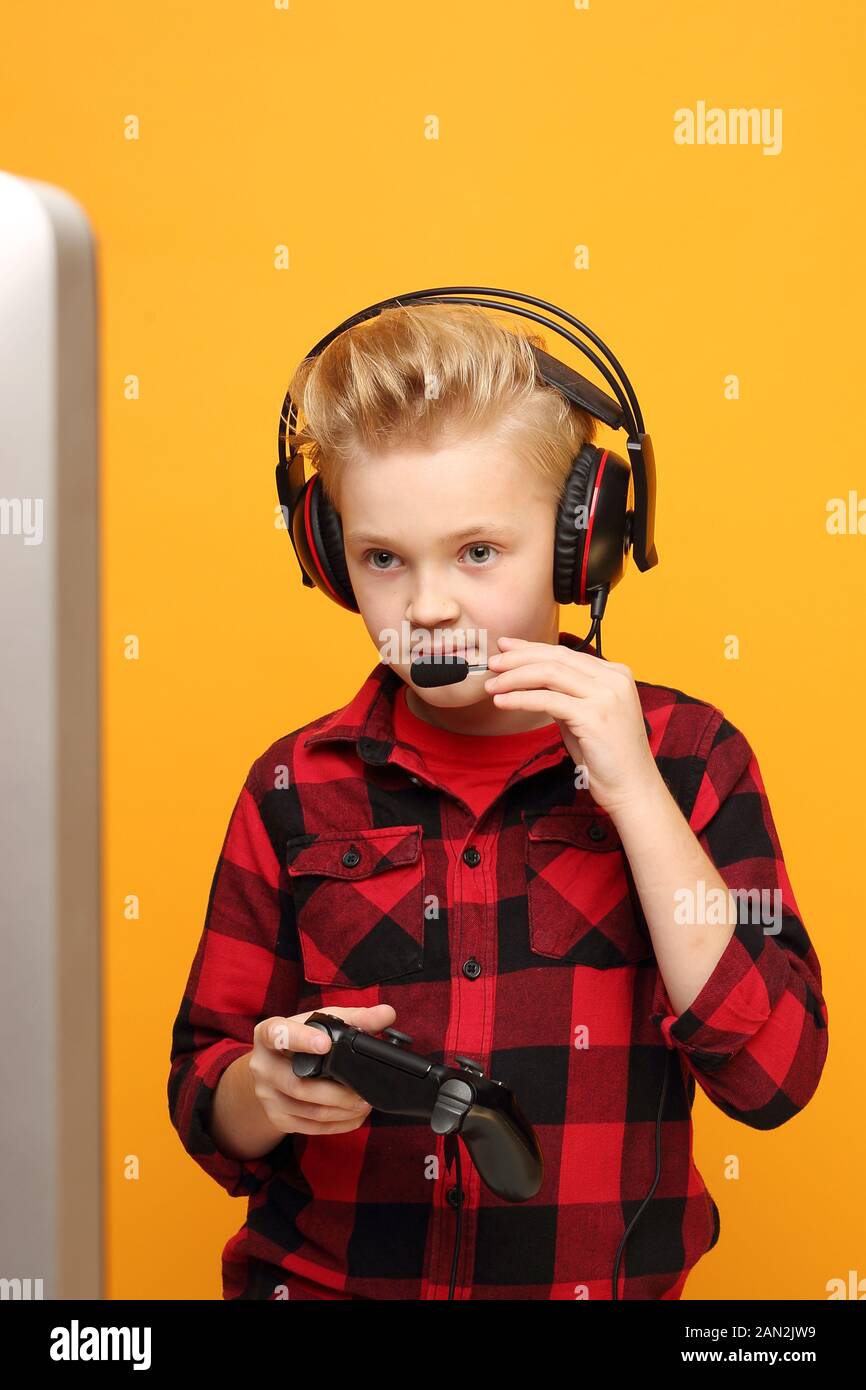 Child boy plays video games in headphones. Young handsome smiling ...