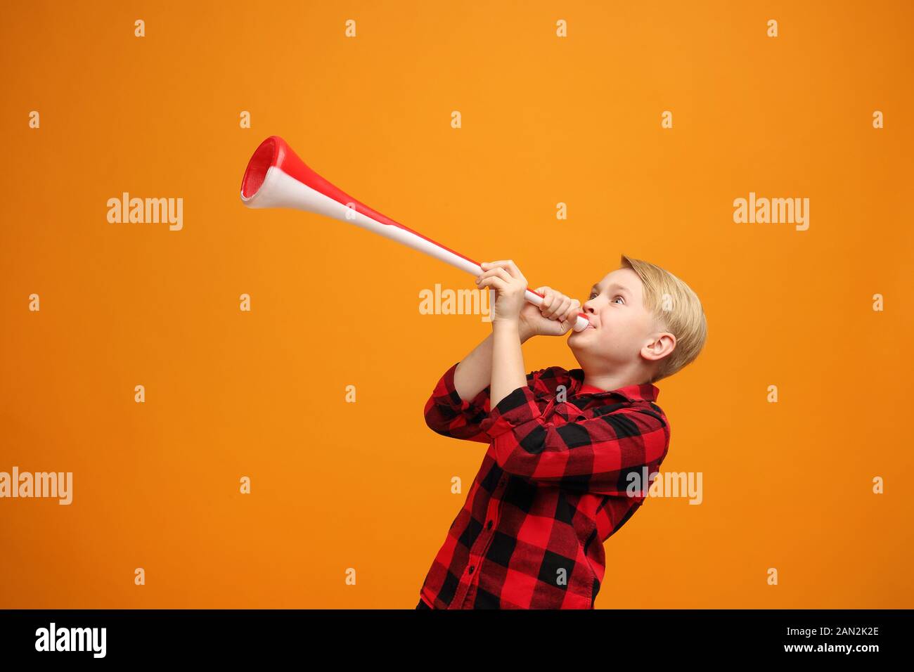 Boy with a big fan trumpet. Beautiful smiling caucasian boy in the red ...