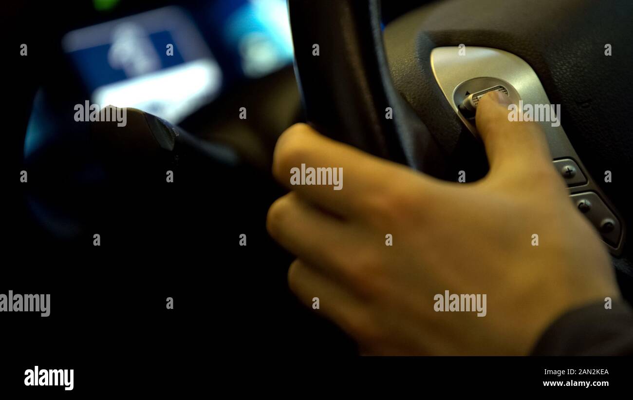 Driver hand pressing source button on steering wheel, testing modern ...