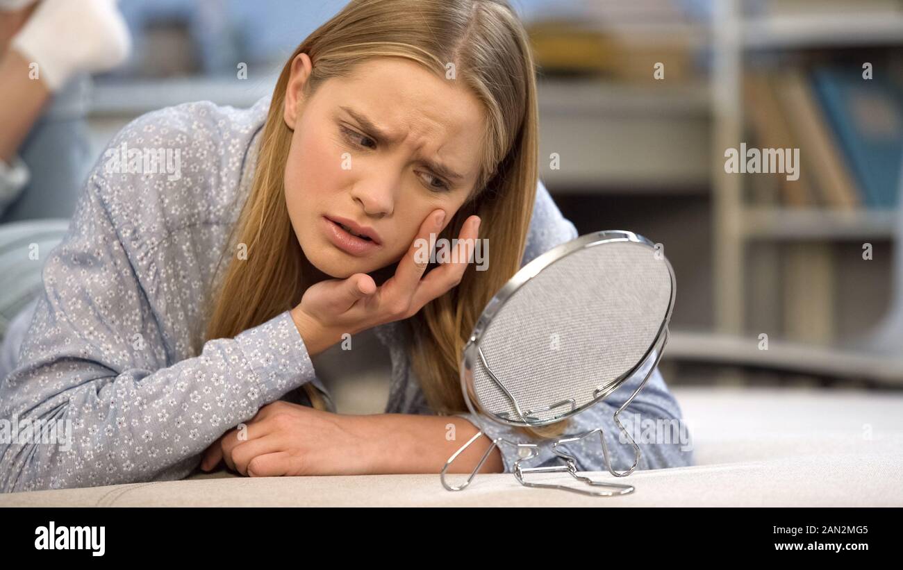 Self-criticism, upset teenage girl looking at her problematic skin ...