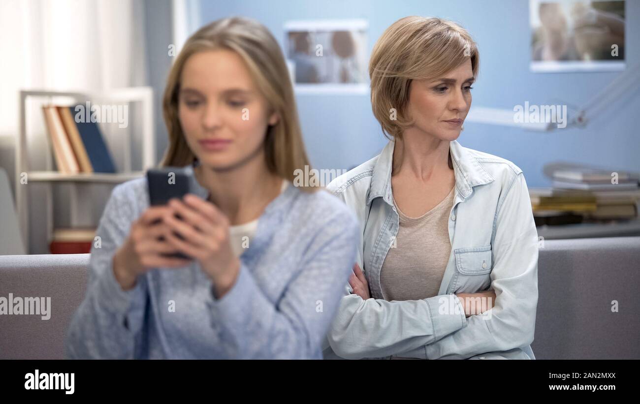 Daughter with smartphone in hands ignoring her mom, indifference ...