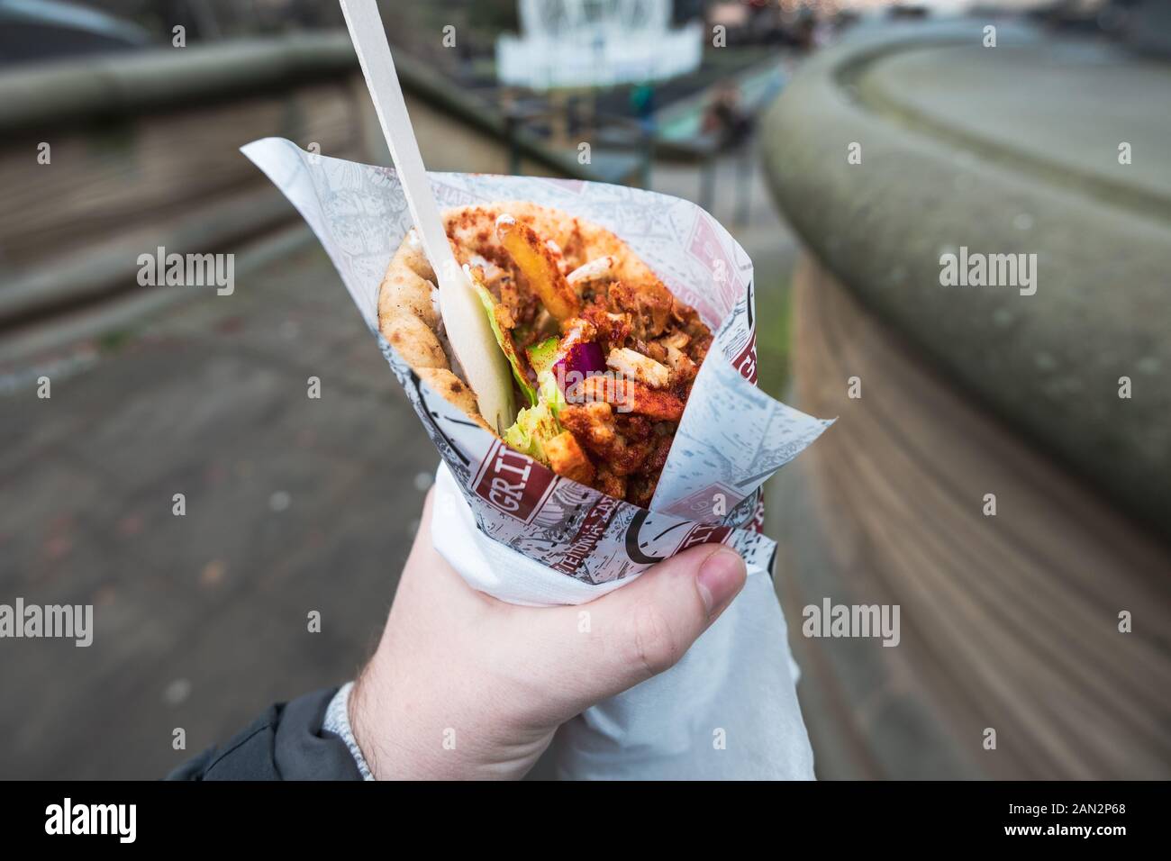 POV of a man holding and eating Gyro outside. Traditional Greek fast ...