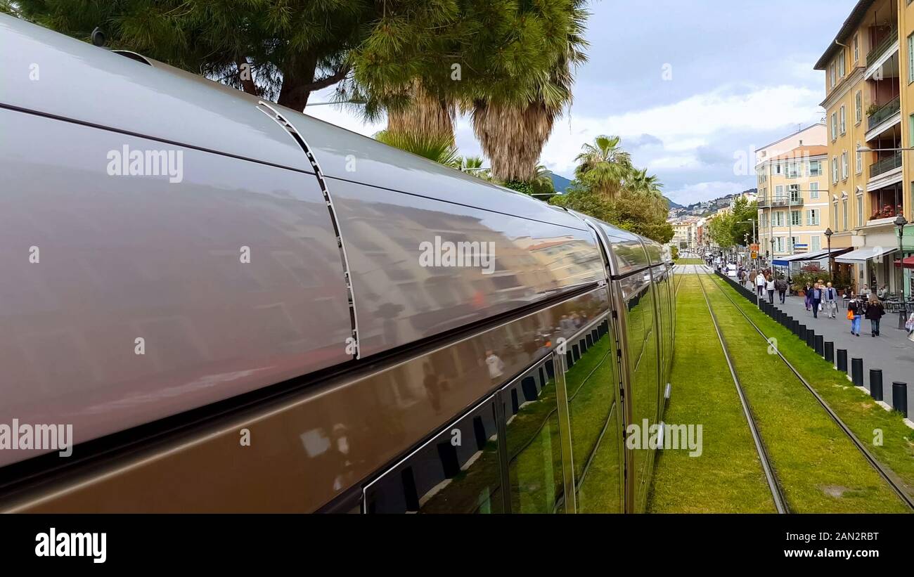 High-speed city train moving on railways along green urban street ...