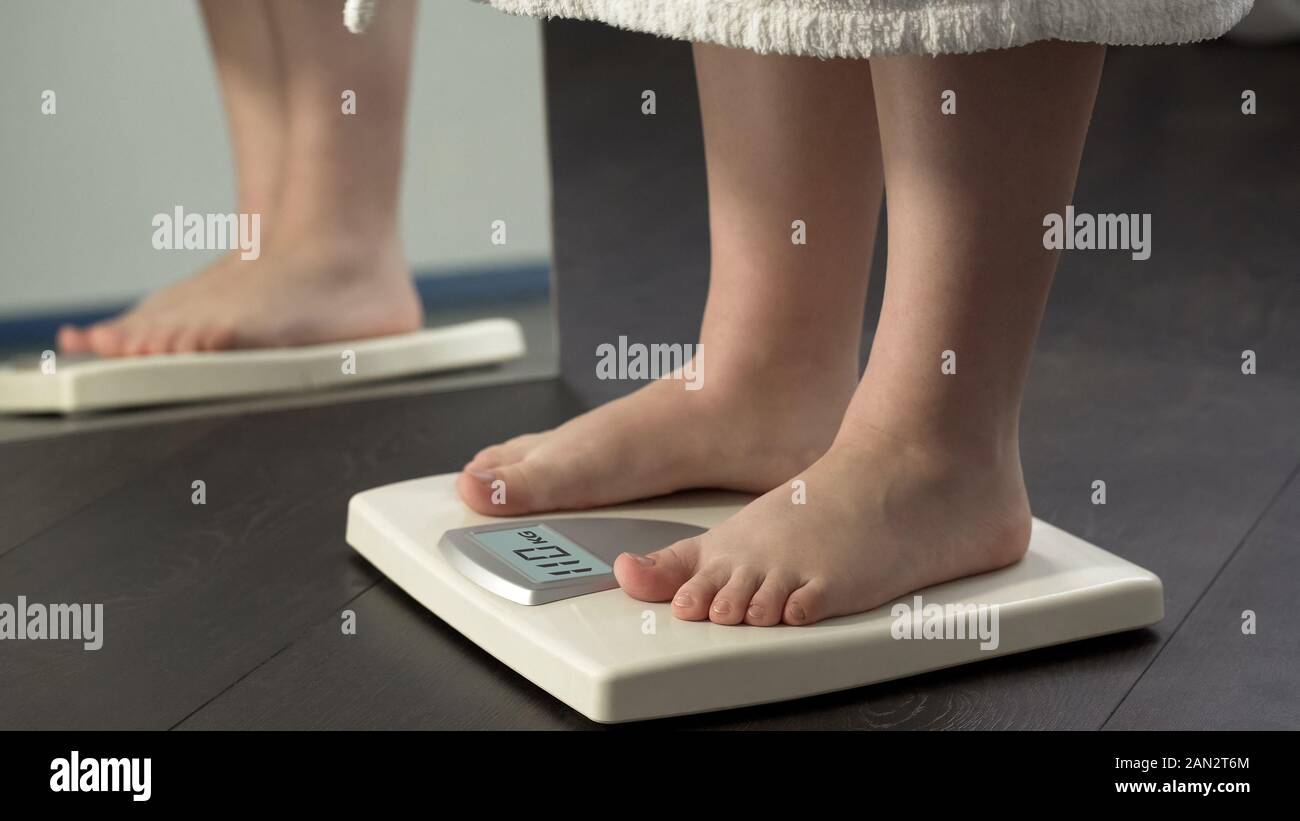 Weight problems, lady standing on scales at home to check weight, extra ...