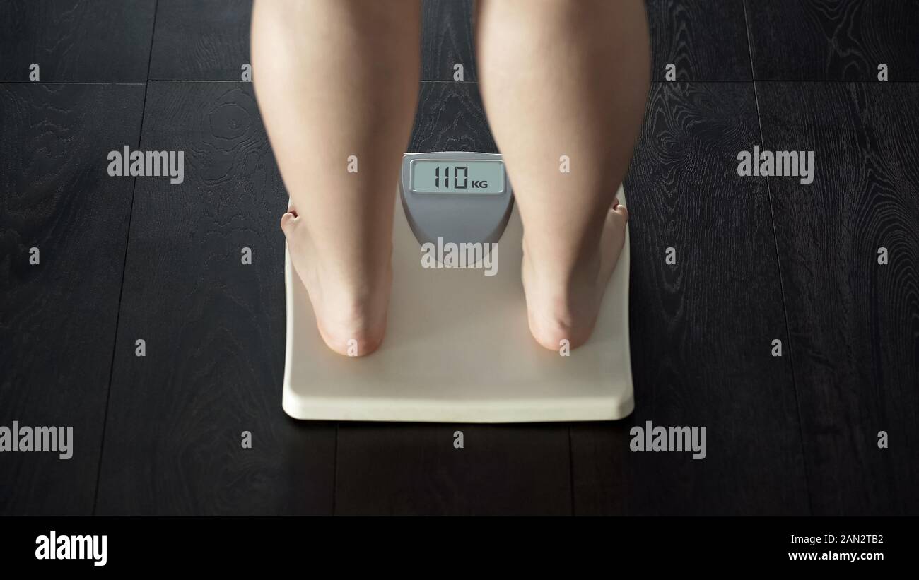 Overweight woman standing on scales to measure weight of body, health ...