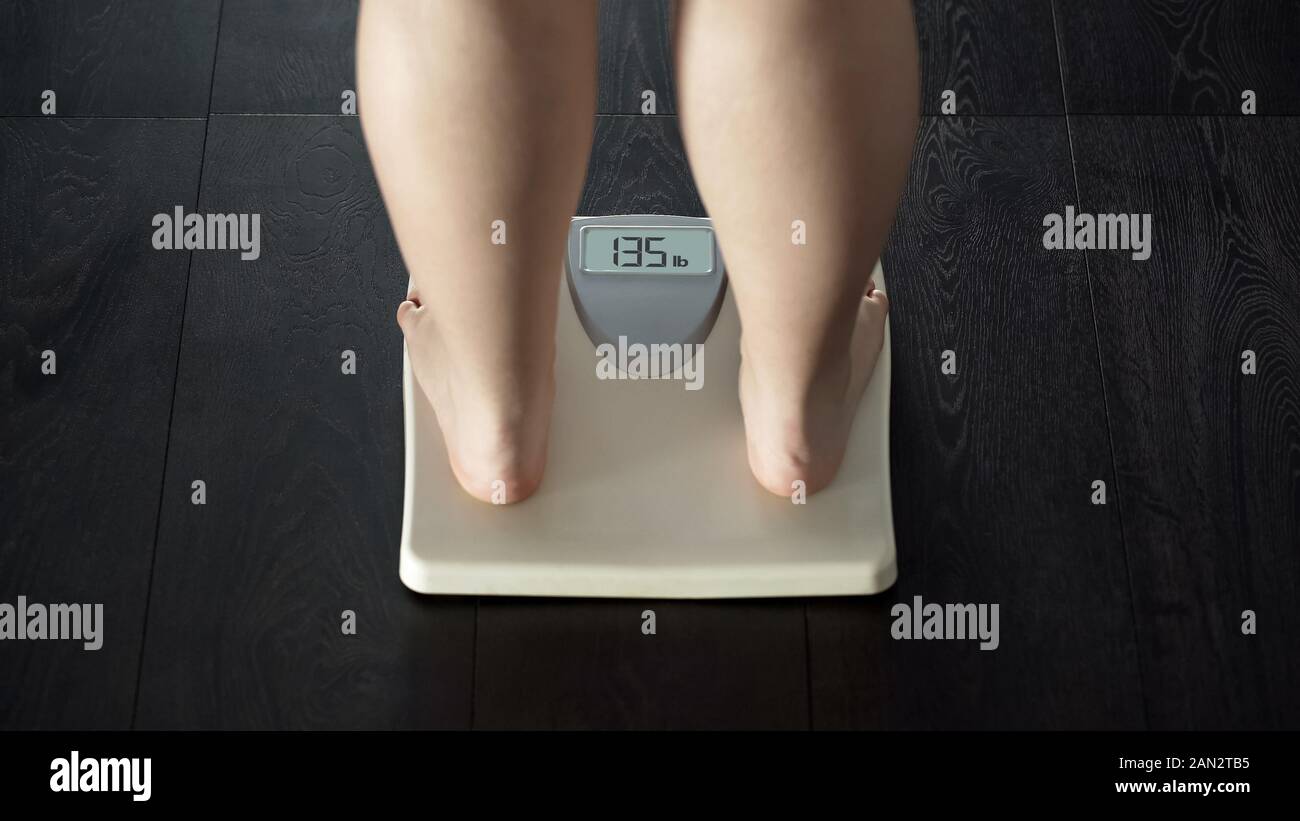 Woman checking her body weight, standing on bathroom scales, normal ...