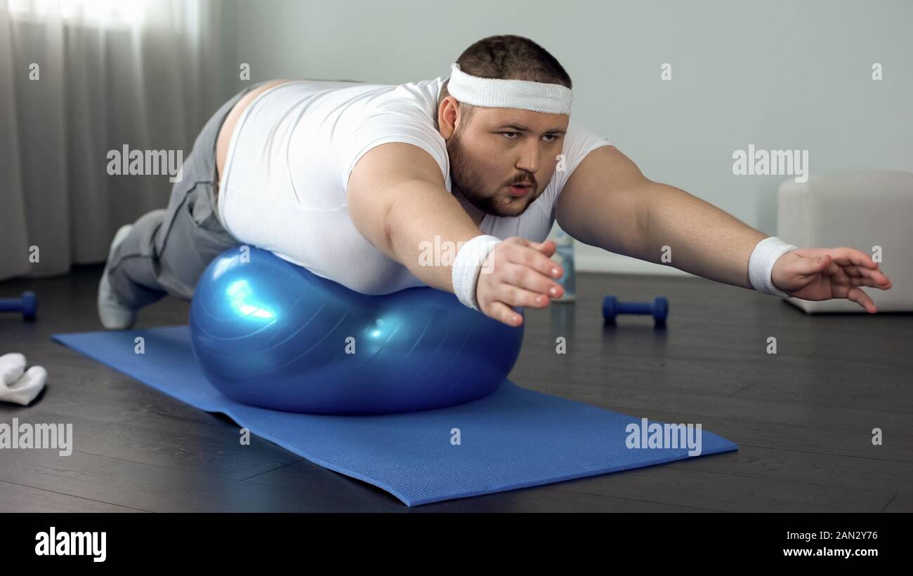 Obese hardworking man practicing static exercise, strength training ...