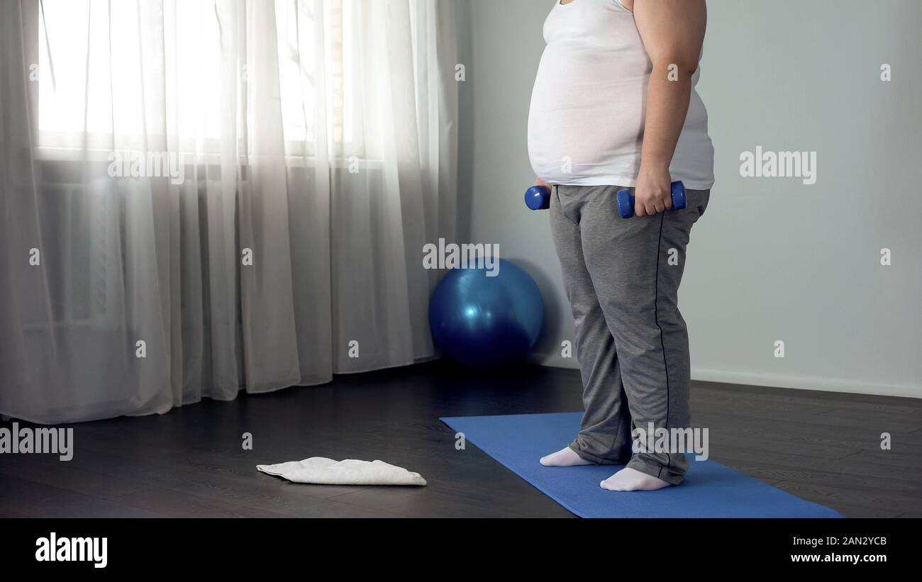 Obese man lifting dumbbells, working out at home, burning calories ...