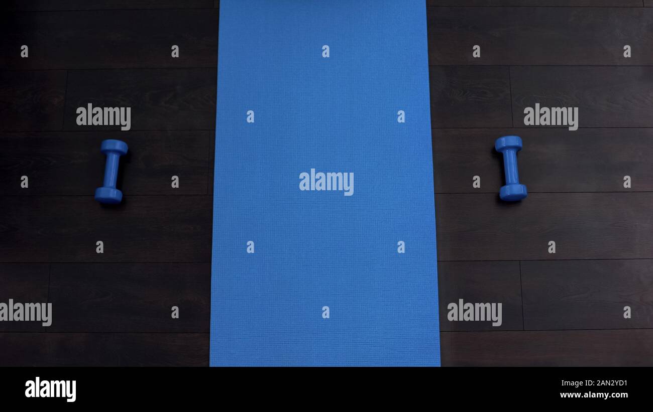Empty fitness mat on floor of gym, dumbbells lying on both sides ...