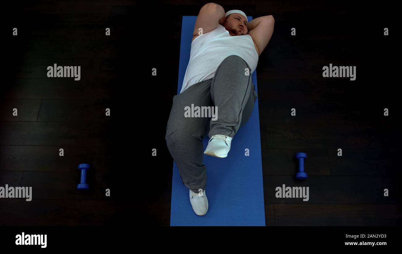 Hardworking fat man doing twist crunches, forcing himself, sport ...