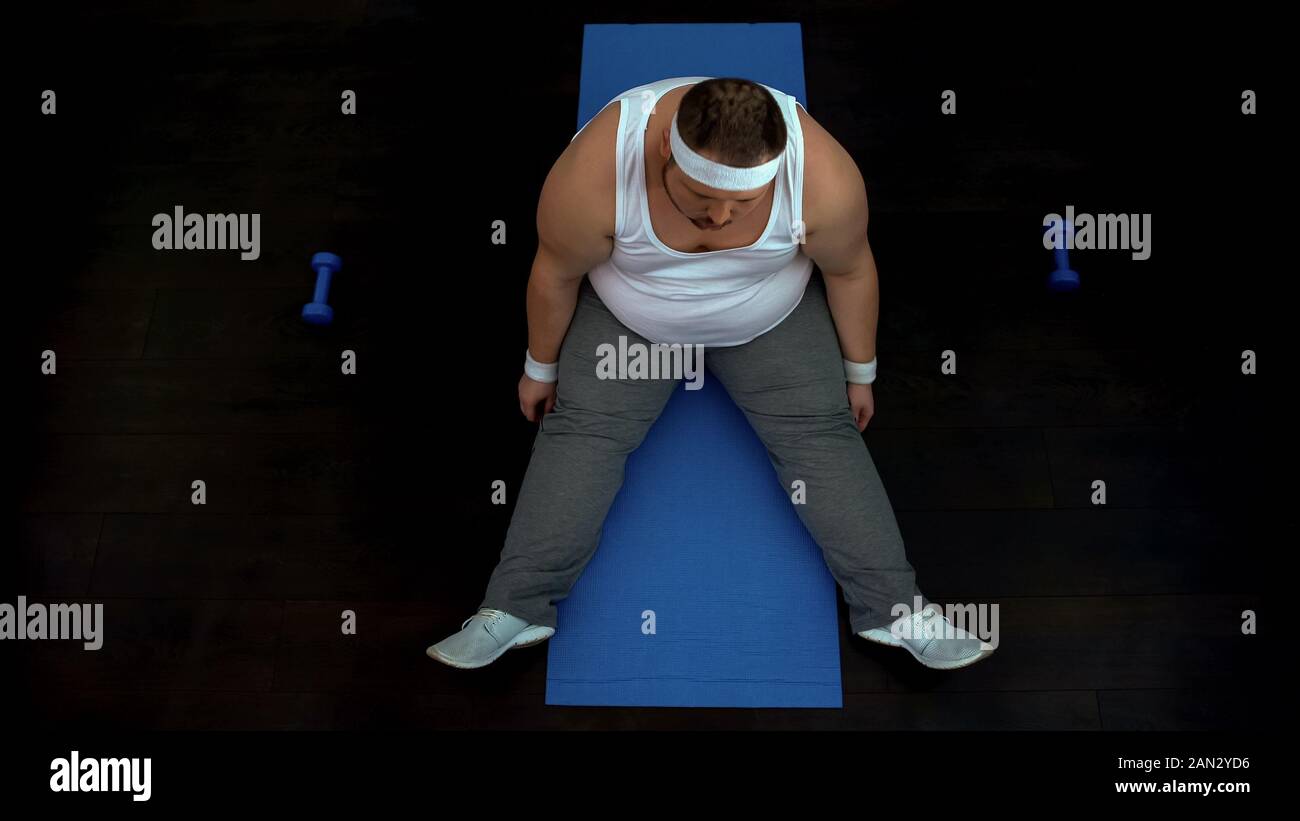Tired overweight man relaxing on mat after home workout, slimming ...