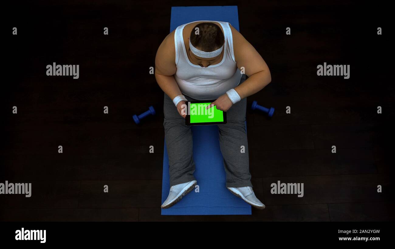 Obese man scrolling application on tablet with green screen instead of ...