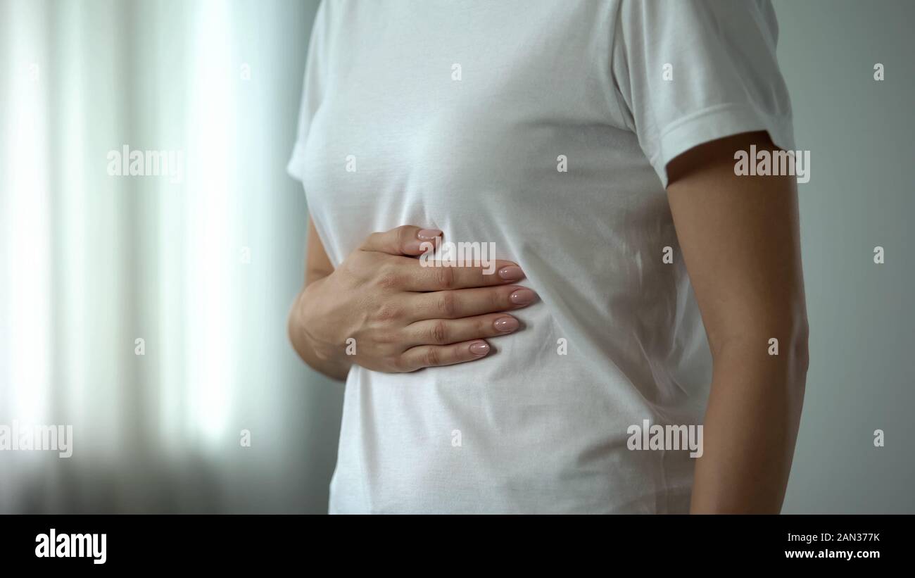 Female touching belly, feeling discomfort in stomach after overeating ...