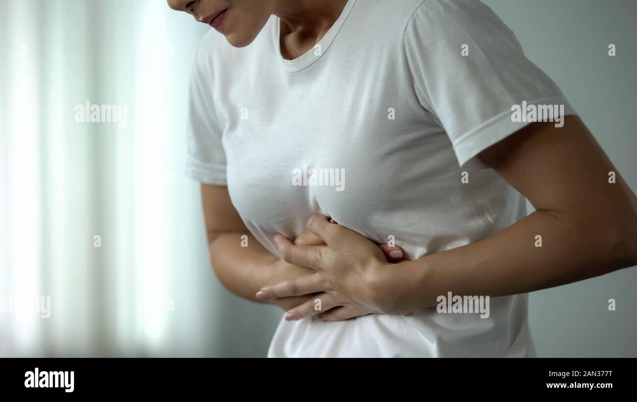 Young woman touching belly, suffering from sharp stomach ache ...