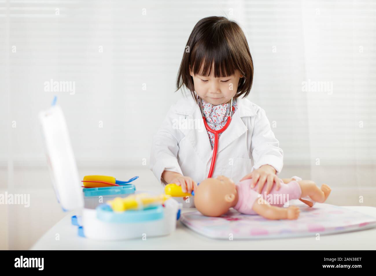 toddler girl pretend play doctor role at home against white background ...