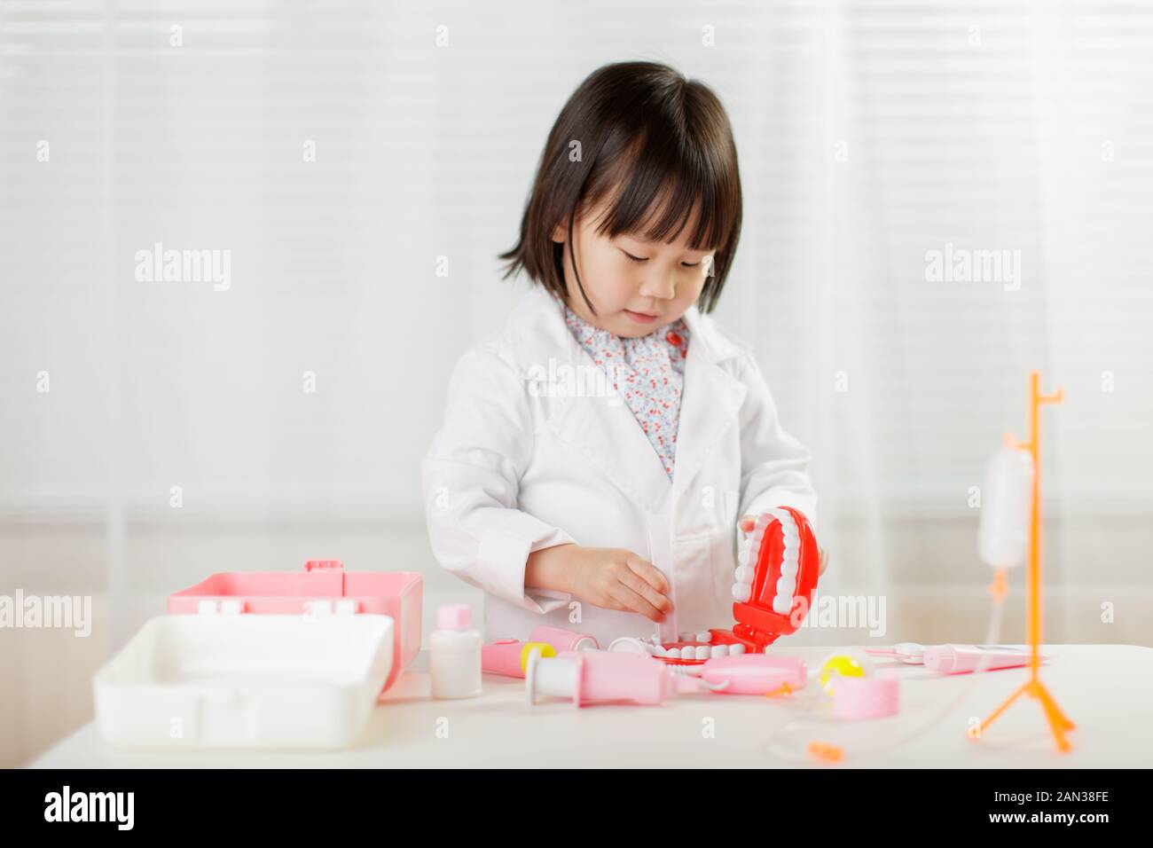 toddler girl pretend play doctor role at home against white background ...