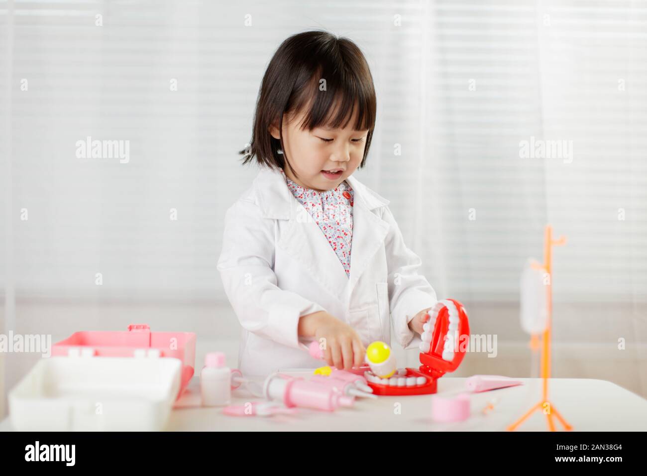 toddler girl pretend play doctor role at home against white background ...
