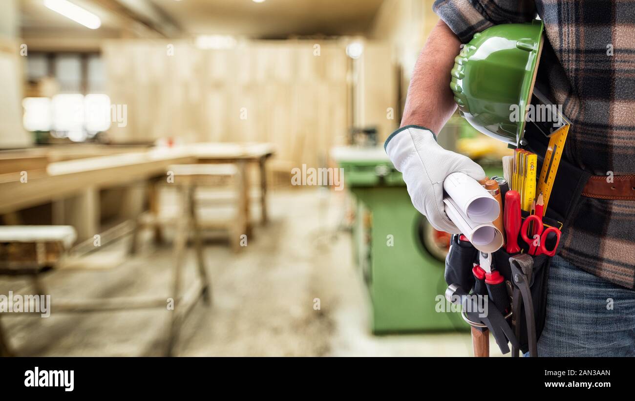 Close-up. Carpenter with his hands protected by gloves holds the helmet ...